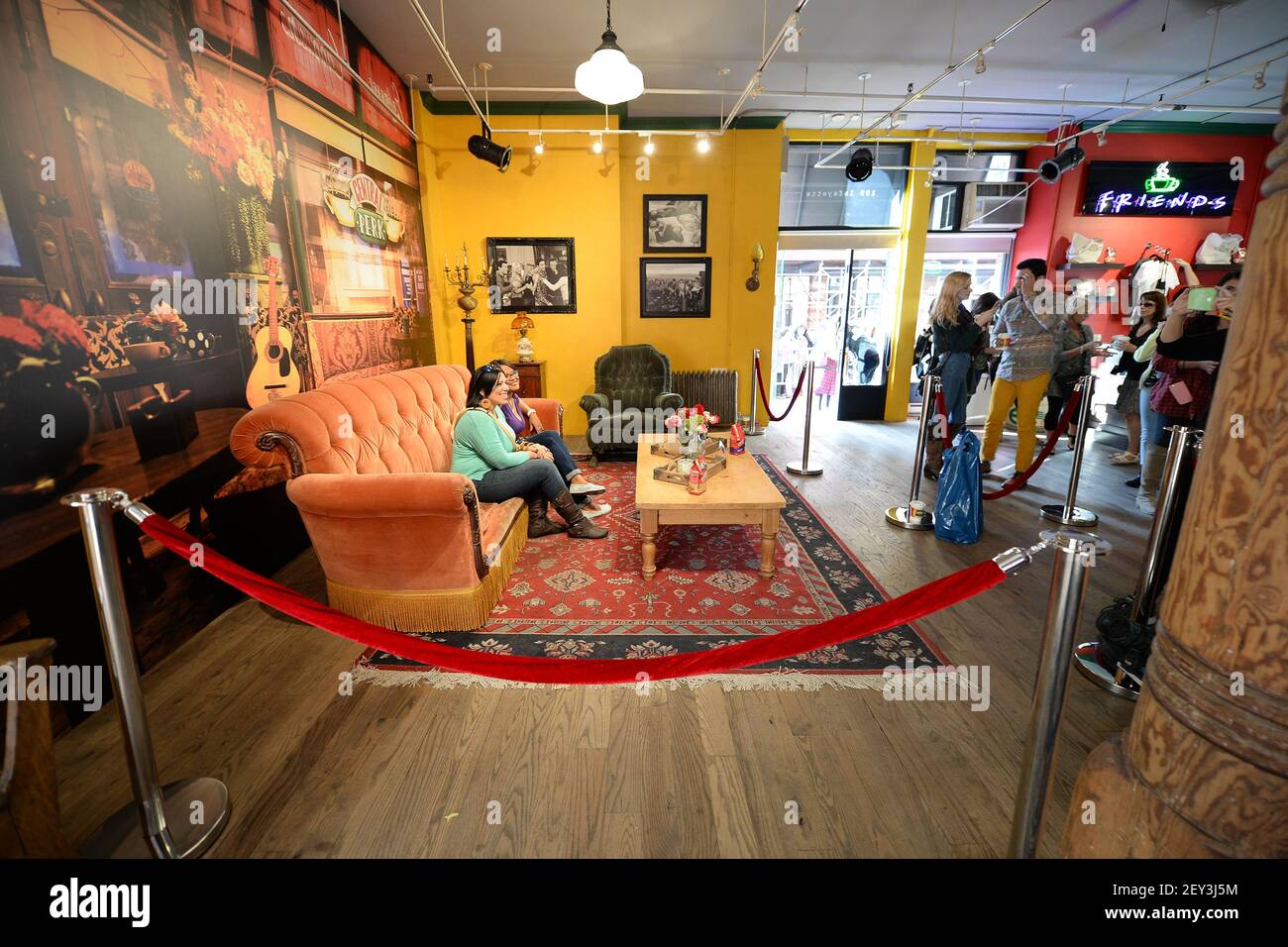 Friends pose for photographs on a replica of the couch and set of ...