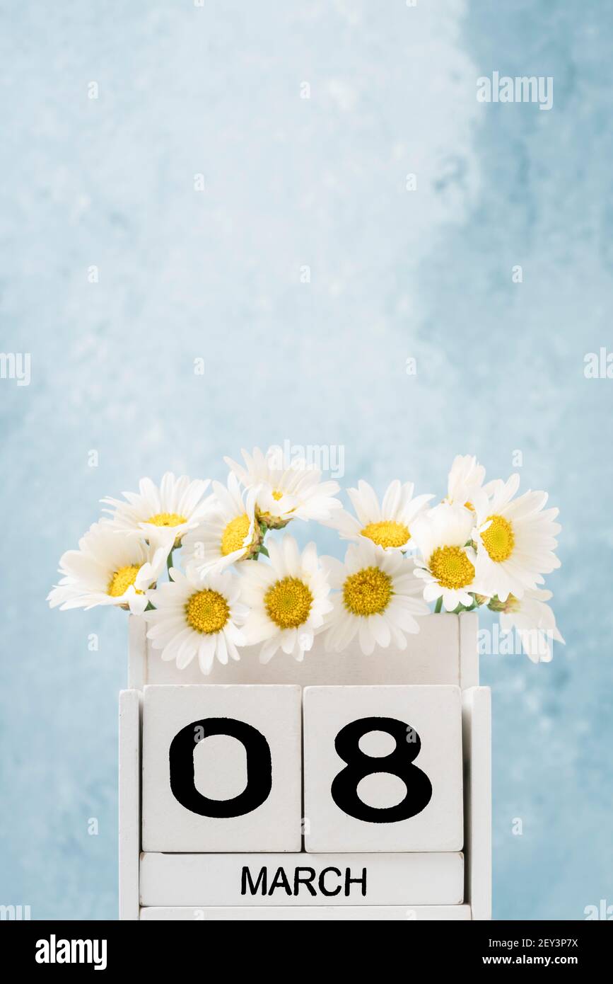 White cube calendar for march decorated with daisy flowers over blue ...