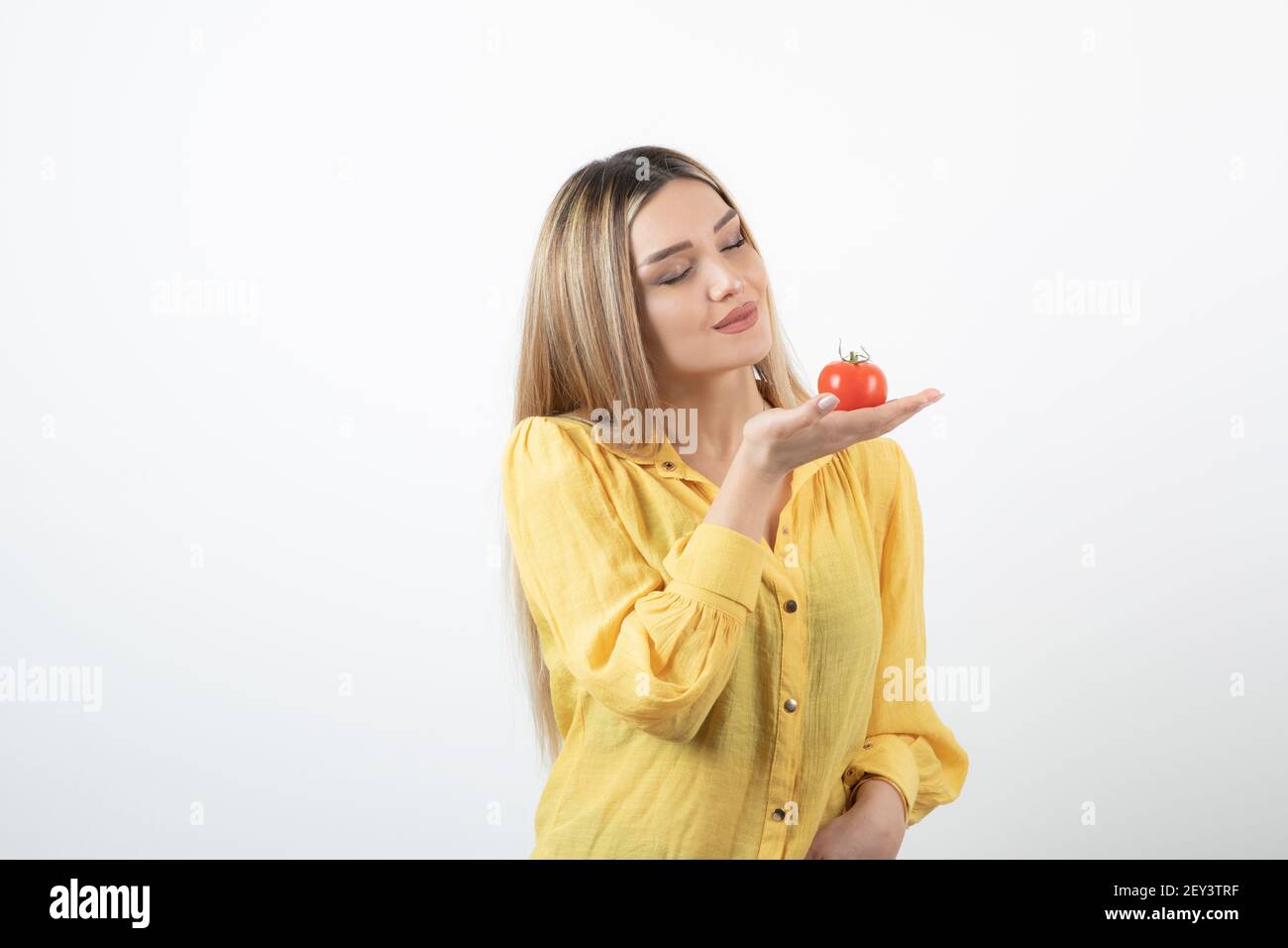 Image of pretty woman looking at red tomato on white background Stock ...