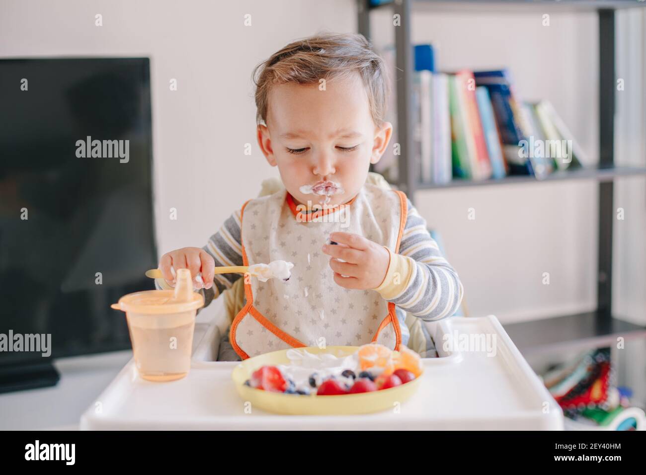 Cute Caucasian baby boy eating ripe berries and fruits with yogurt ...