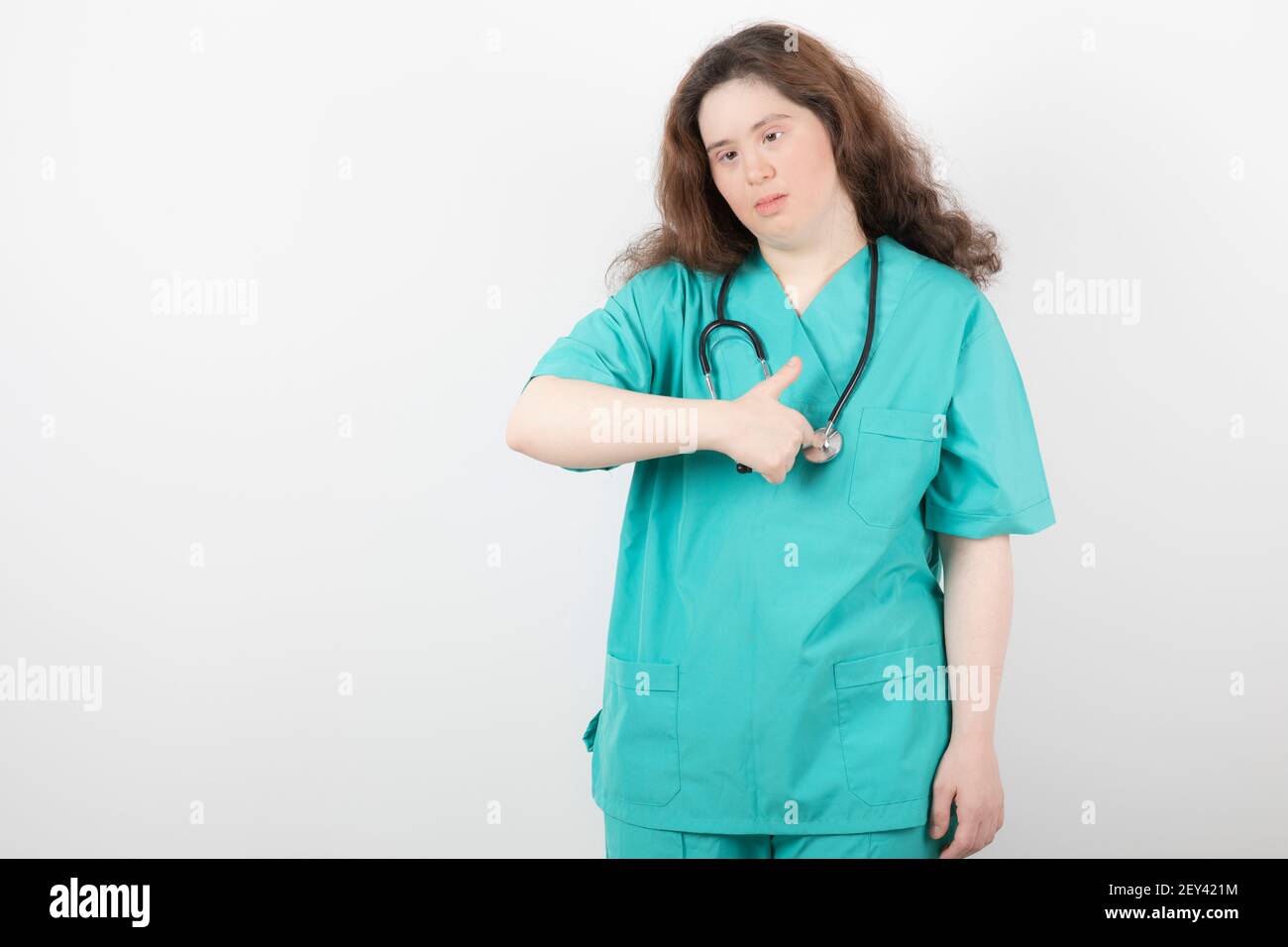 Young female doctor with down syndrome giving thumbs up on white ...