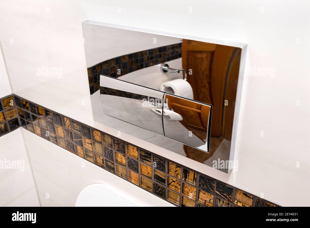 A chrome plated toilet flush with two buttons placed in the wall of a ...