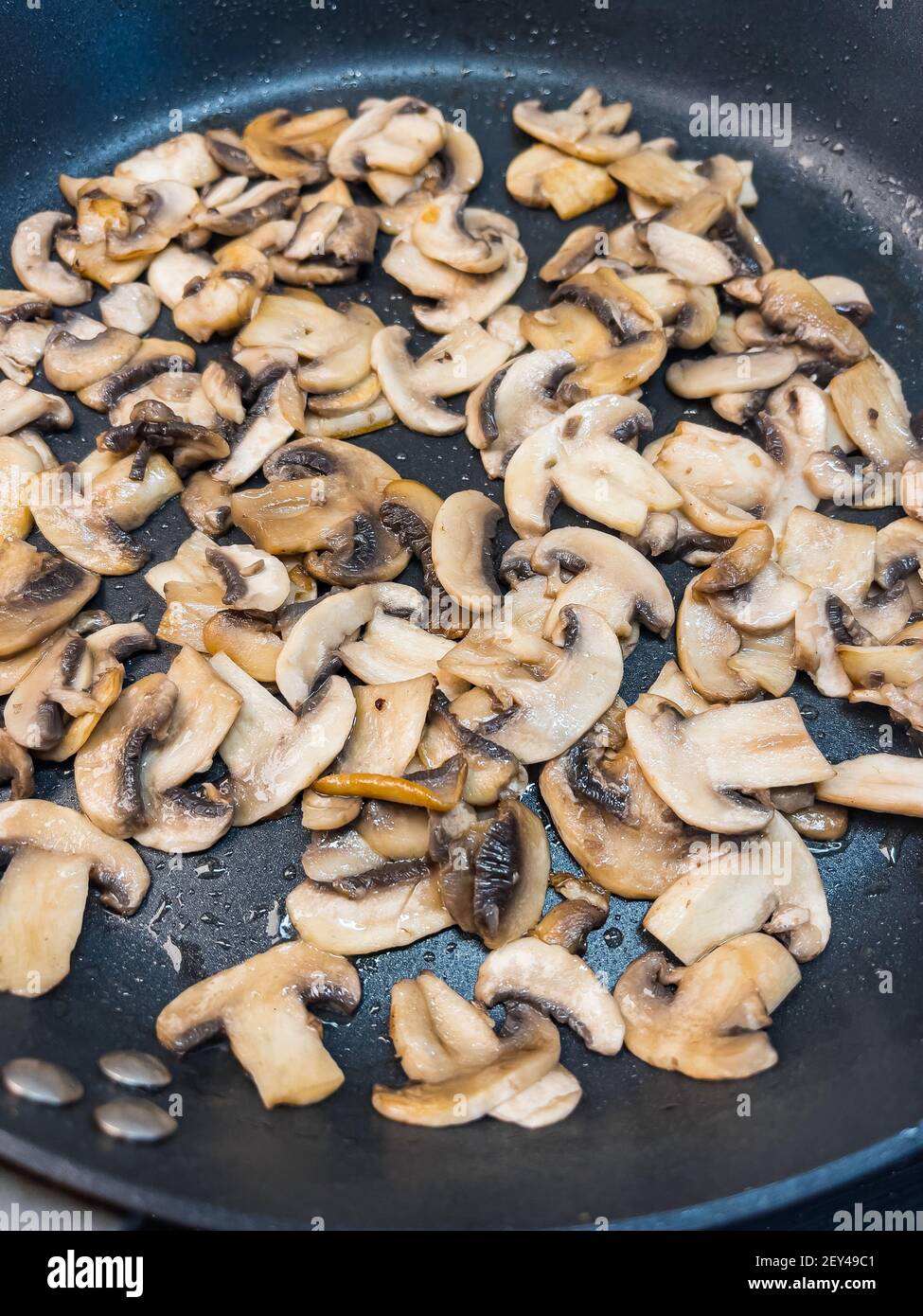 Close up of fried cut mushrooms in pan, top view Stock Photo - Alamy