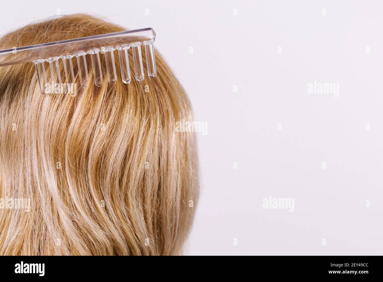 Hair care. Darsonval in comb shape and female blonde girl hair ...