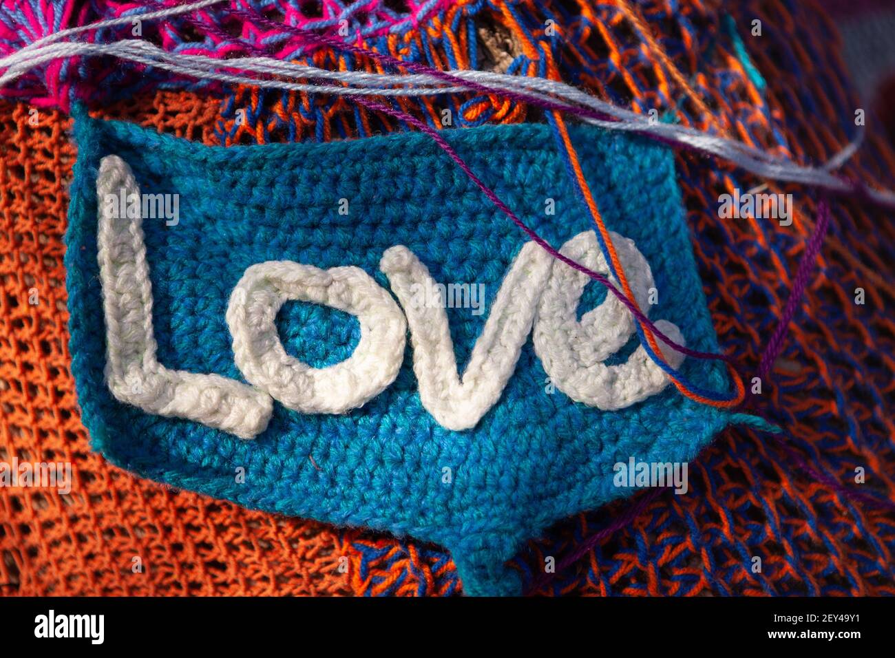 A closeup of a piece of knit fabric written "love" on a blue background ...