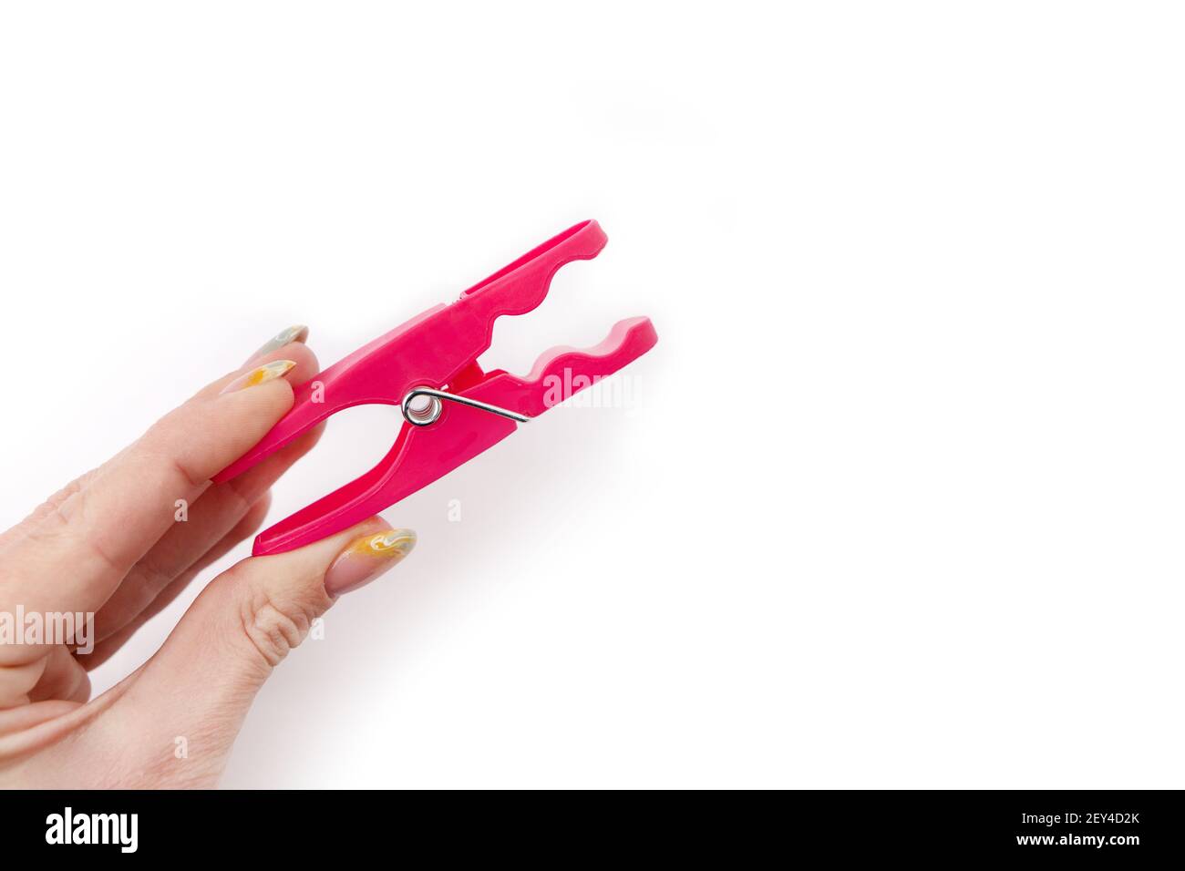 female hand holding a clothespin of pink color isolated on white ...