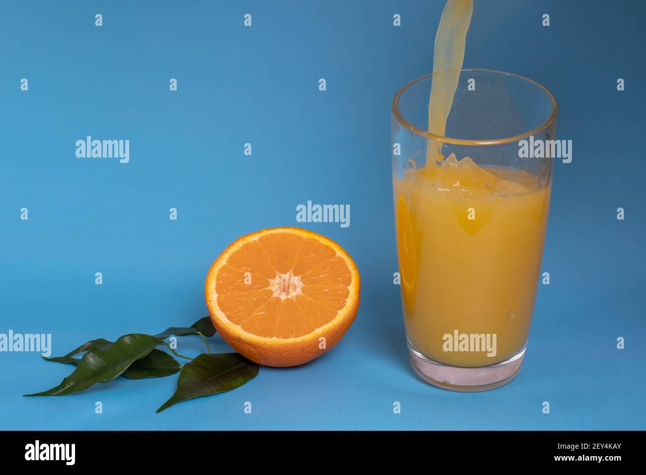 Fresh orange juice is poured into a glass, fruit cut in half and sliced ...