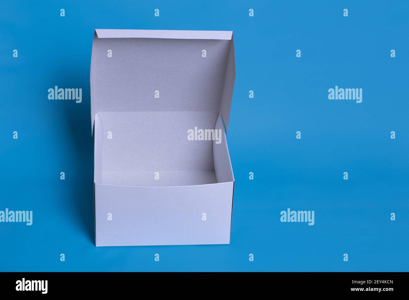 Close up photo of an open white box with shadow on a dark blue ...