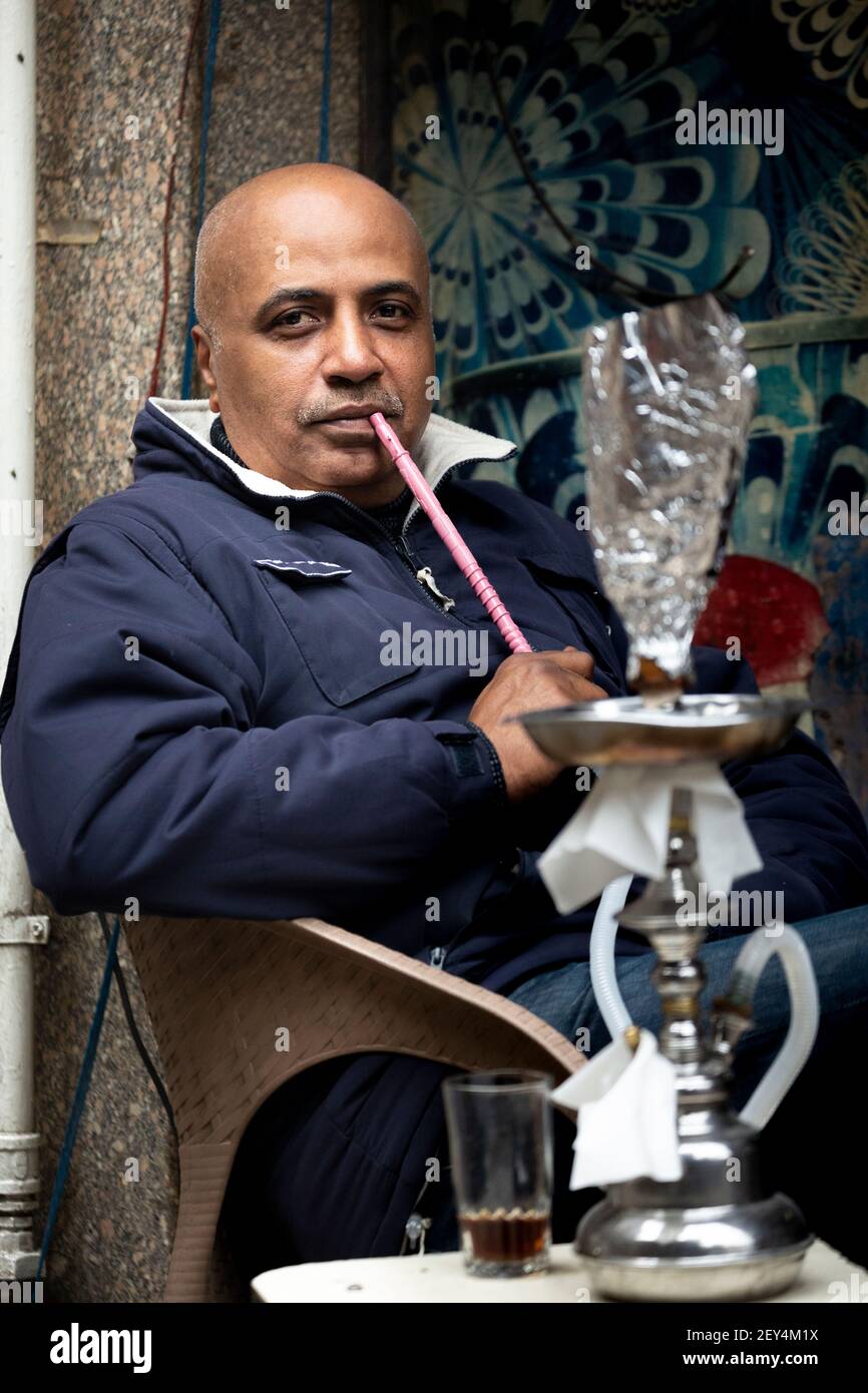 Portrait of a local Egyptian man smoking a shisha pipe at a cafe (ahwa ...