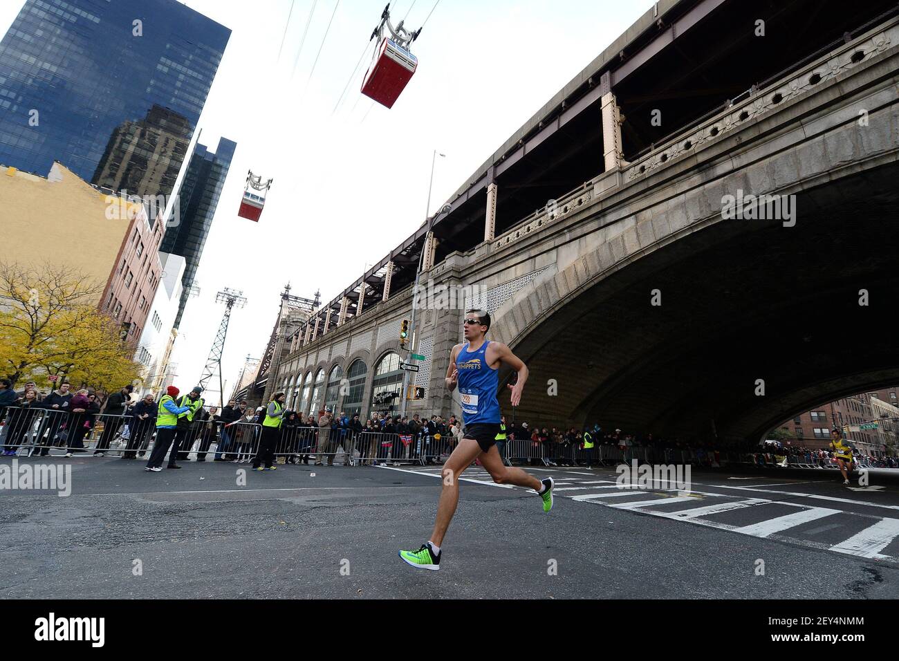 Two Roosevelt trams pass overhead as a runner emerges from the Ed Koch ...