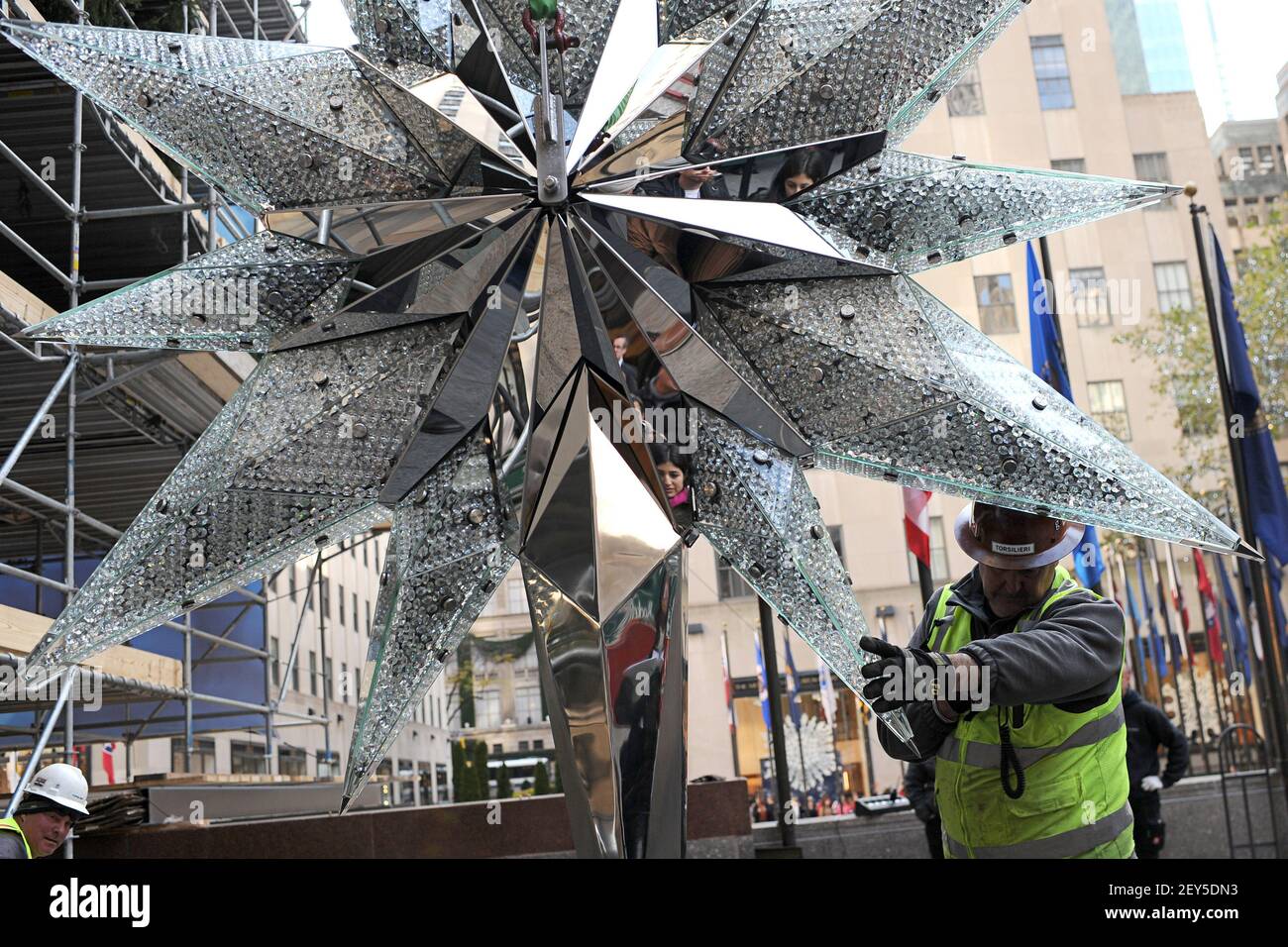 Workers guide the Swarovski Star as it starts its rise toward the top ...