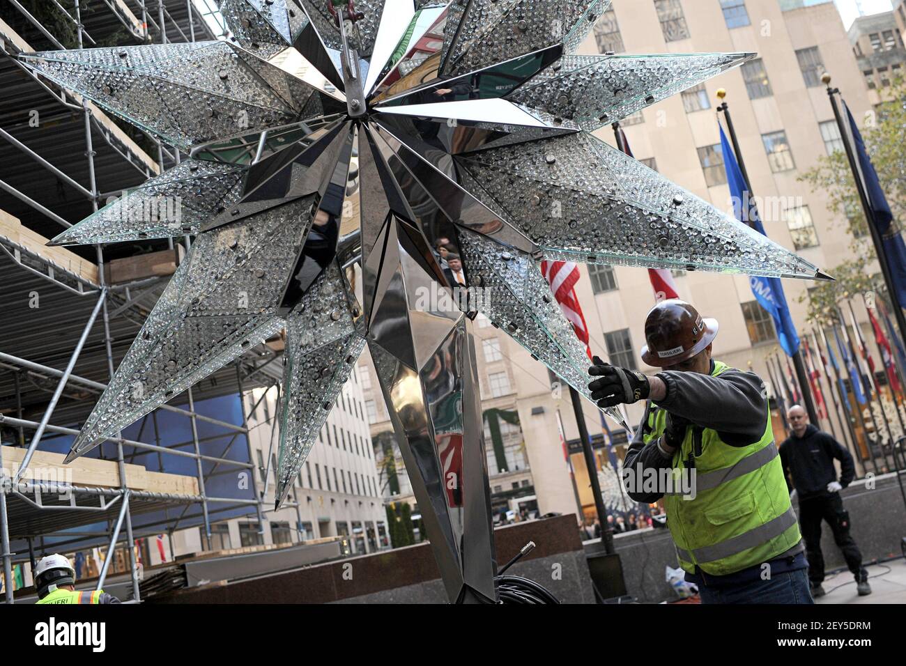 Workers guide the Swarovski Star as it starts its rise toward the top ...