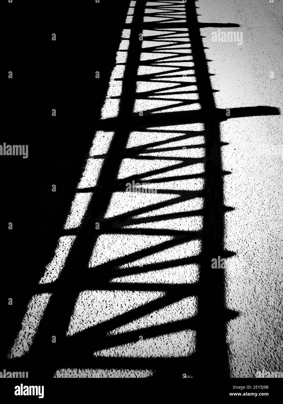 A greyscale top view closeup of the shadow of a railing on a street ... A greyscale top view closeup of the shadow of a railing on a street ...