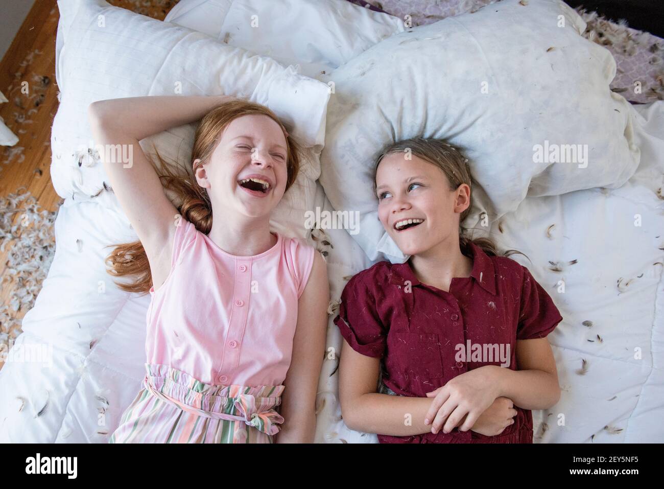 Two happy young girls having a feather pillow fight on the bed Stock ...