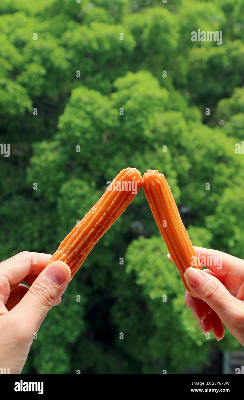 Couple's Hands Clinking Stick of Fresh Fried Churros against Blurry ...