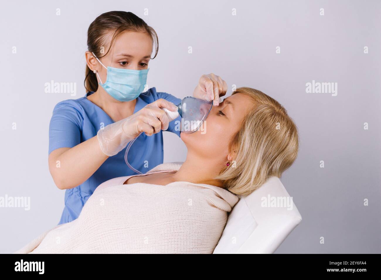 A nurse makes a nebulizer treatment for a Caucasian woman against ...