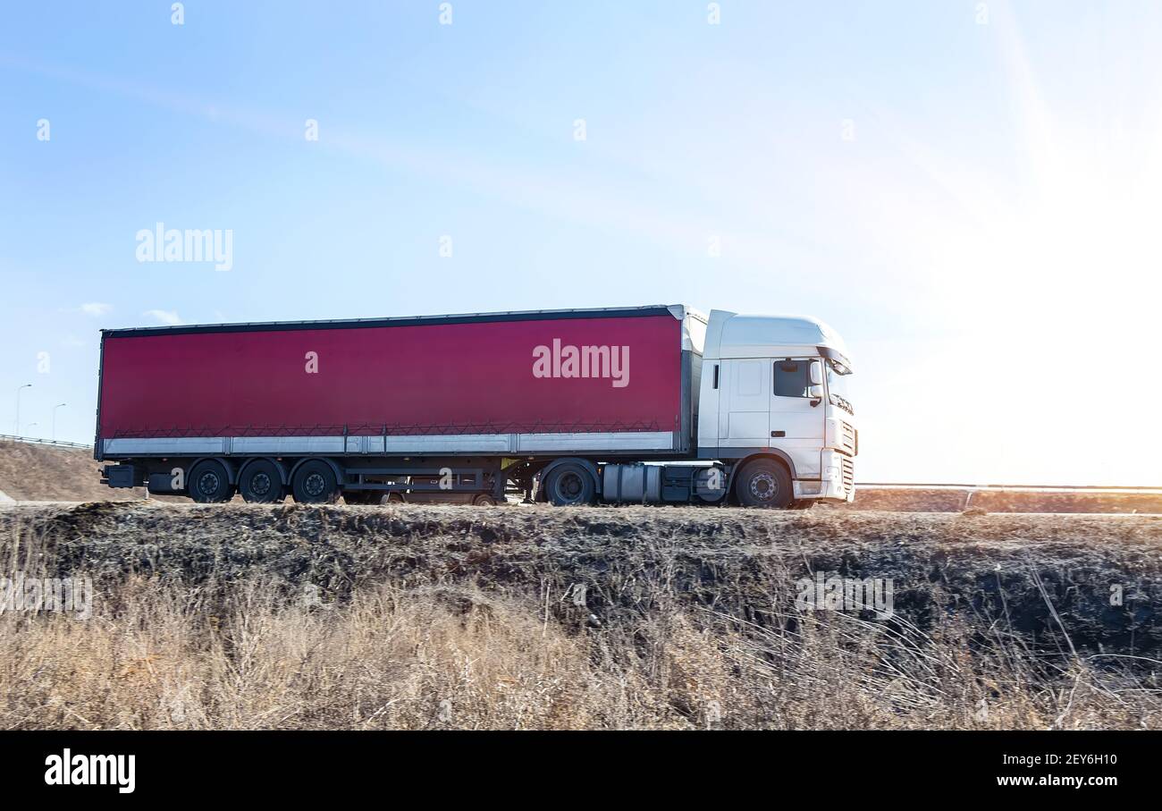 Truck with Container Rides on Highway in sunlight Stock Photo - Alamy