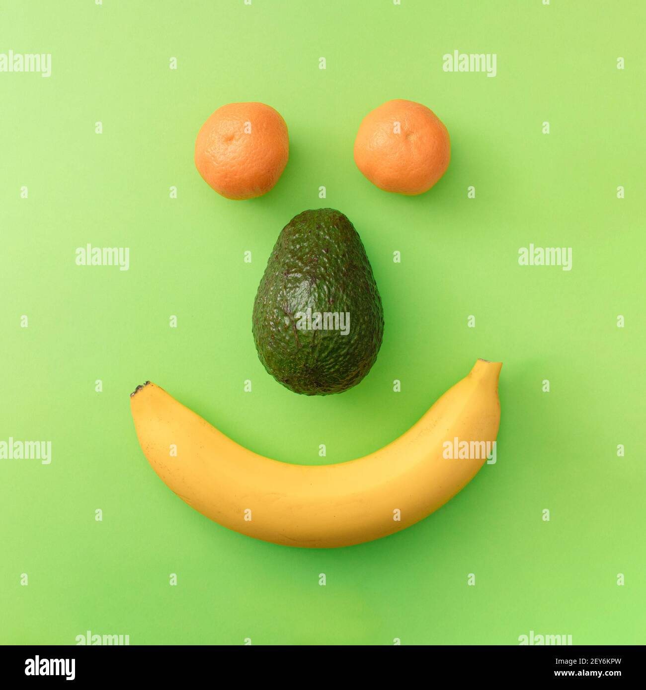 Positive smiley face from banana, avocado and tangerine on a green ...