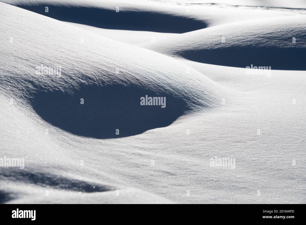 horizontal image of snow mounds in winter time with shadows cast by ...