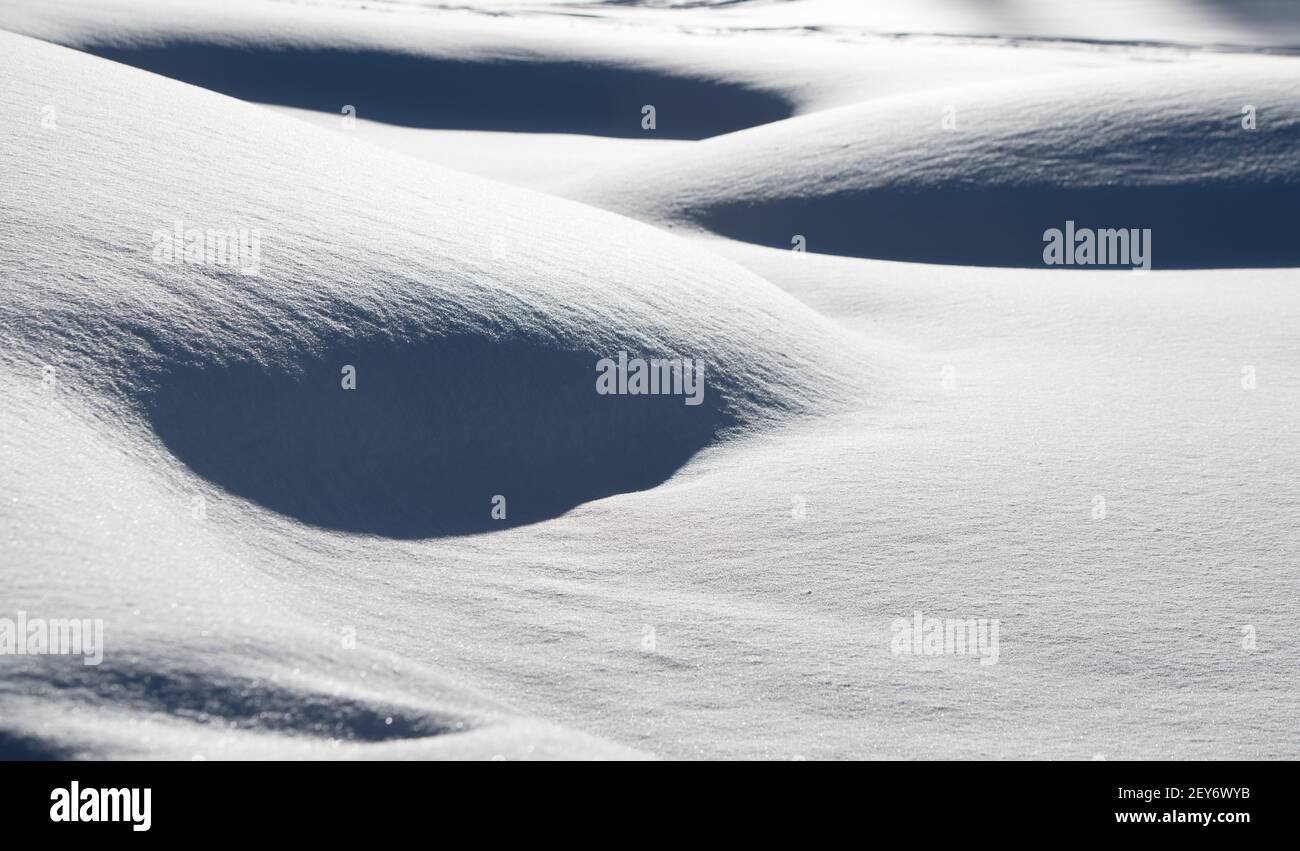 horizontal image of snow mounds in winter time with shadows cast by ...