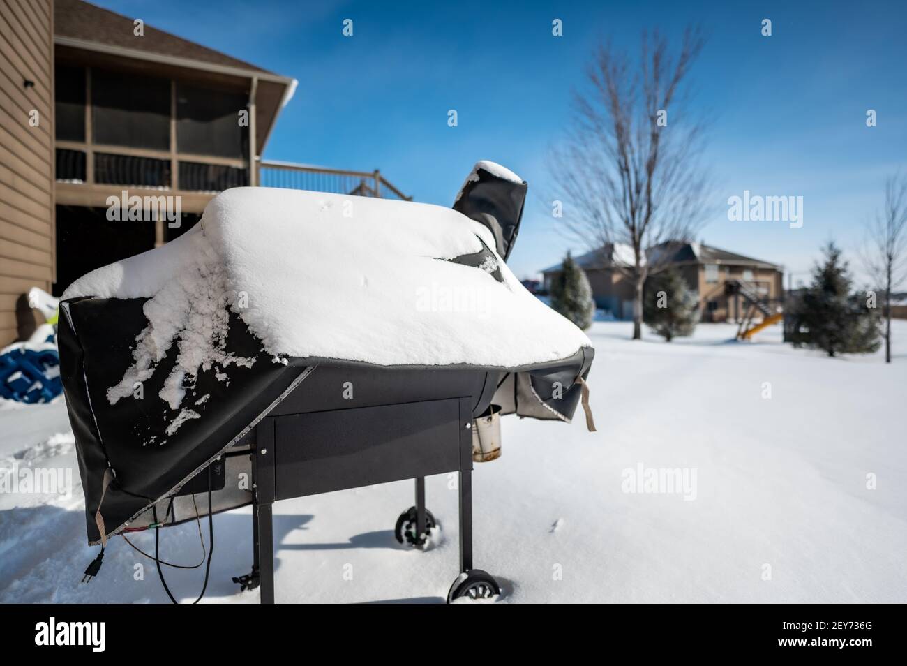 Snow covered BBQ smoker grill in the backyard with winter background ...