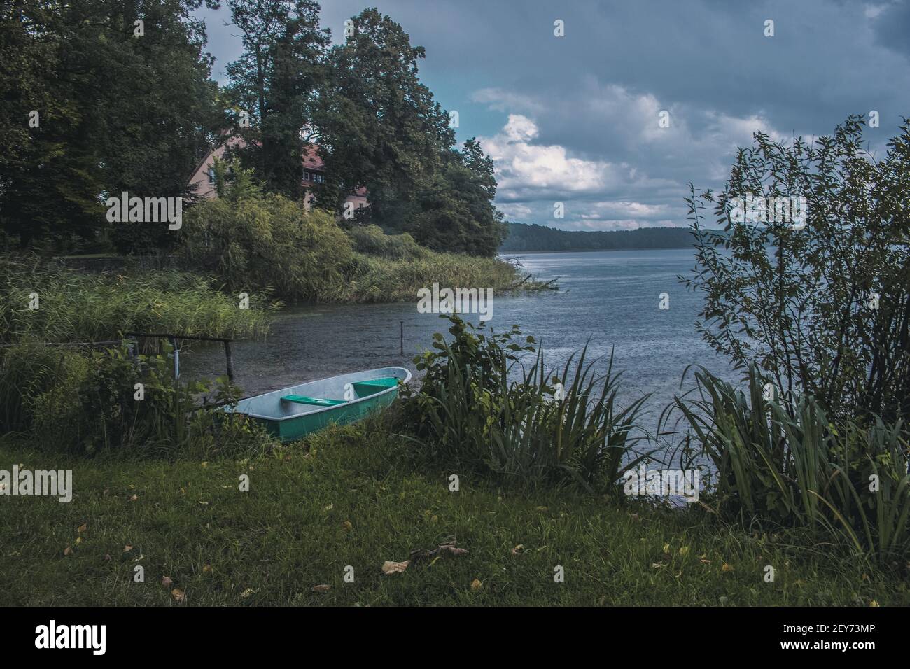 A beautiful view of a green wooden boat parked by a river Stock Photo ...