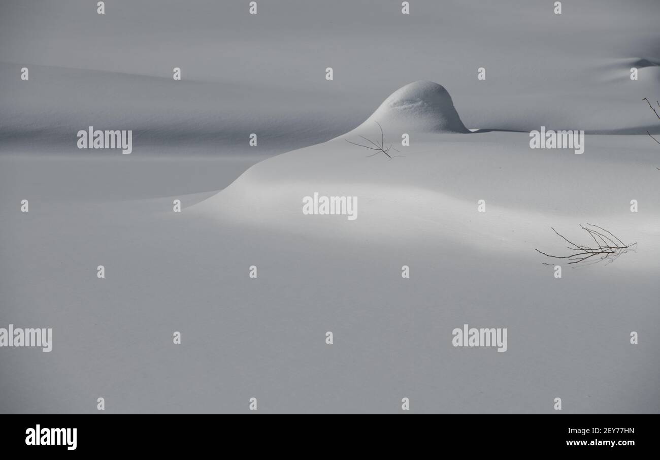 snow mound surrounded by fresh snow curves in white snow shadows and ...