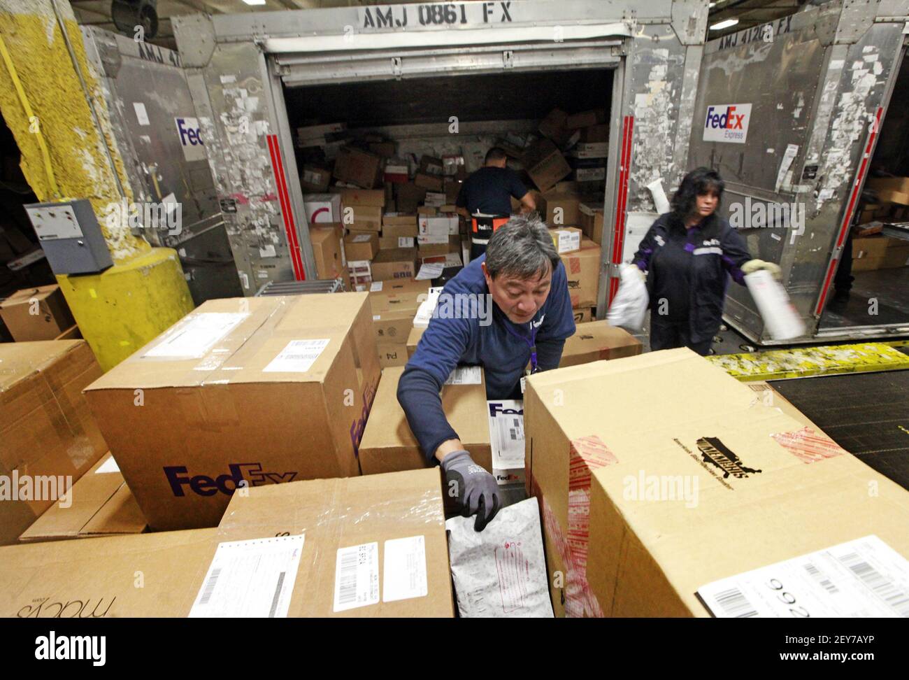 FedEx worker Alejo Pasion unloads packages from an airplane container ...