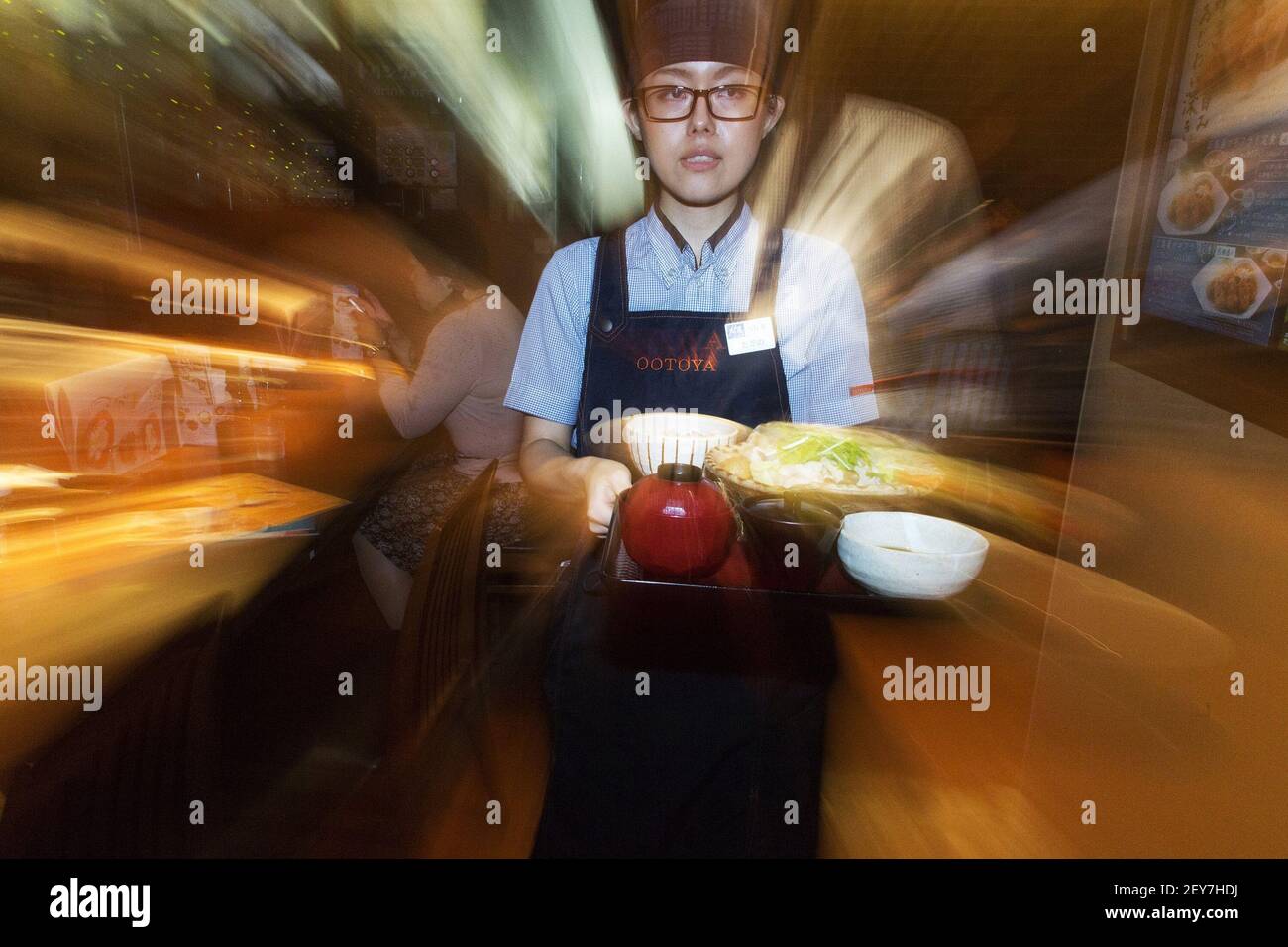 A waitress delivers North Carolina pork to a table at Ootoya in Tokyo ...
