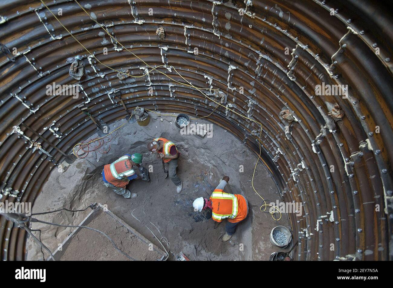 Workers in manhole digging around steel encased microtunnel. as part of ...