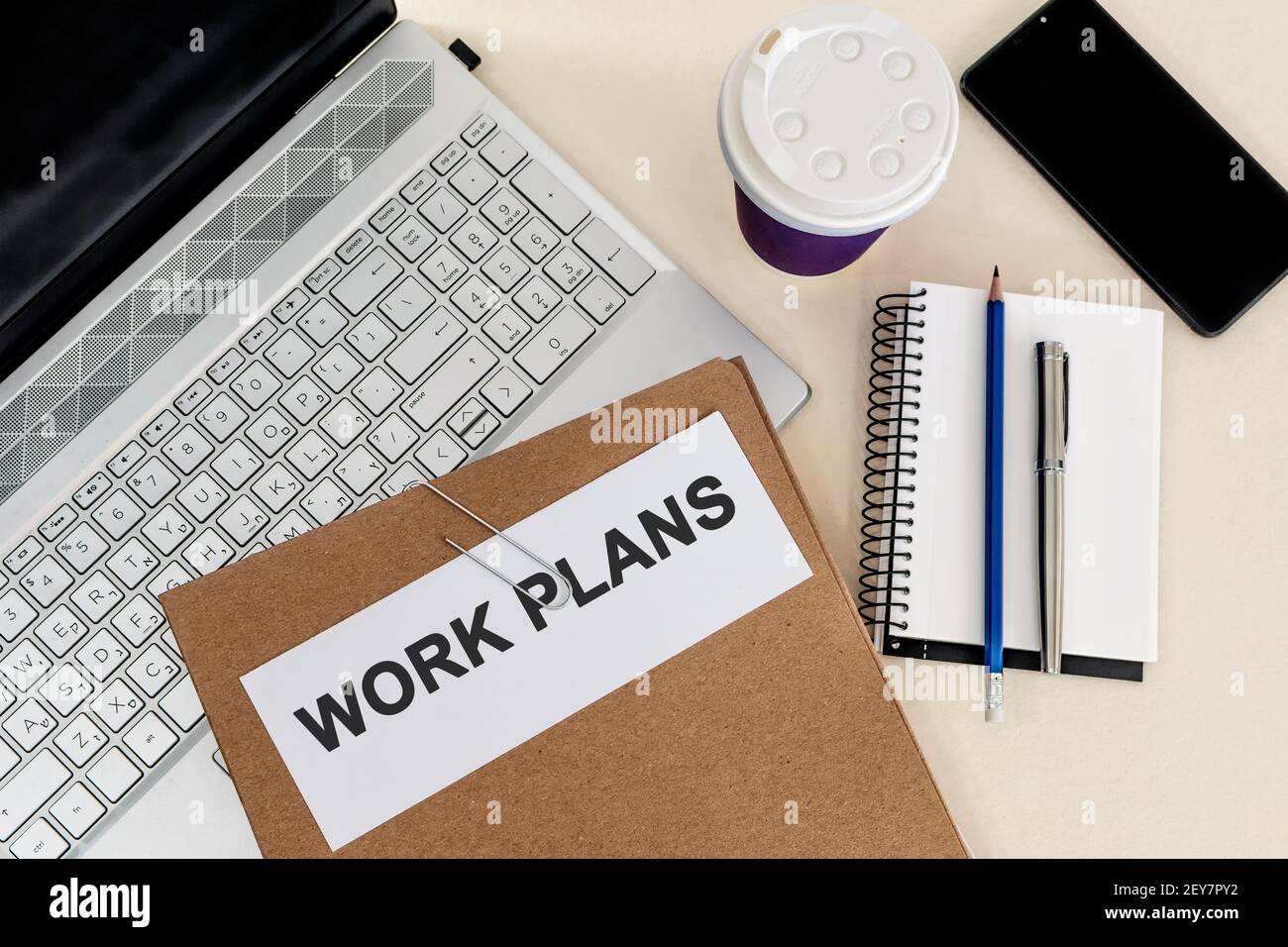 A top view of a folder labelled "WORK PLANS" on a laptop in the office ...