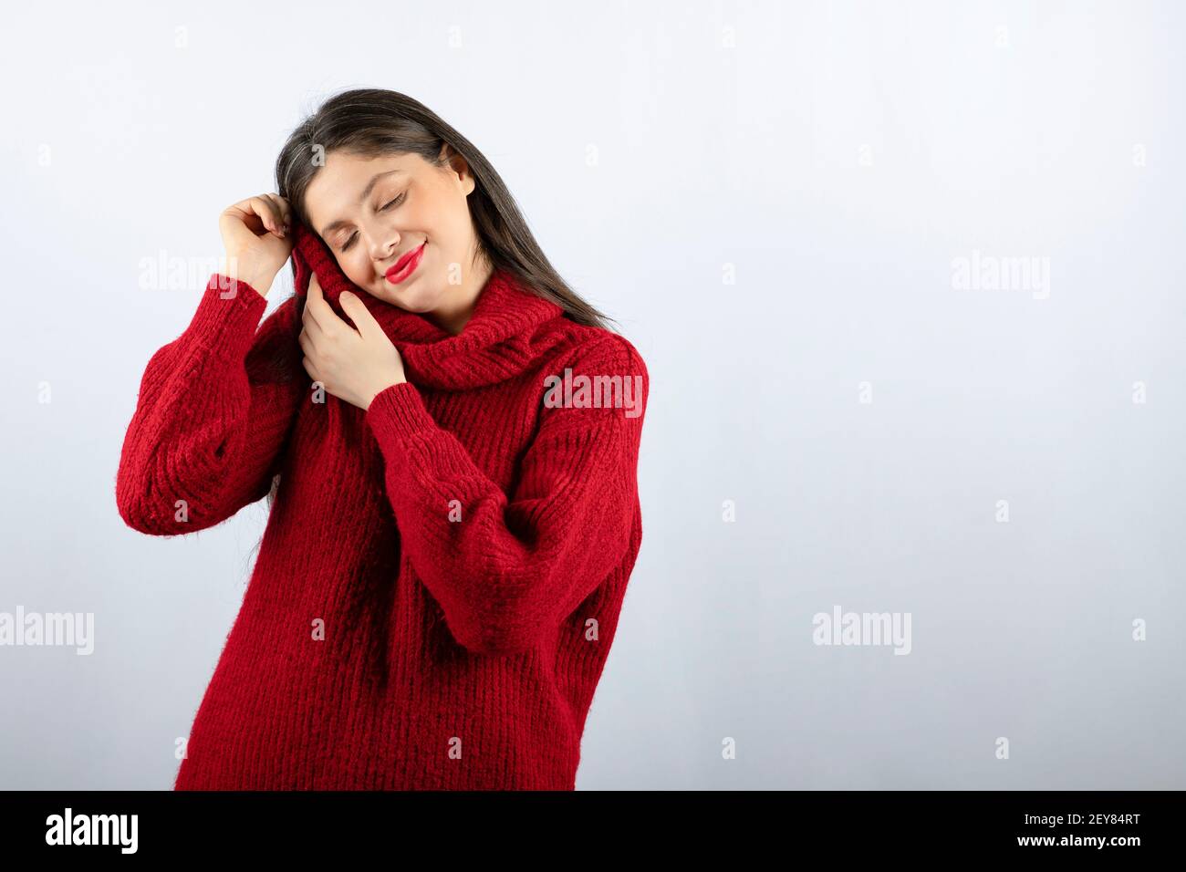 Portrait photo of a young woman model in red warm sweater standing and ...