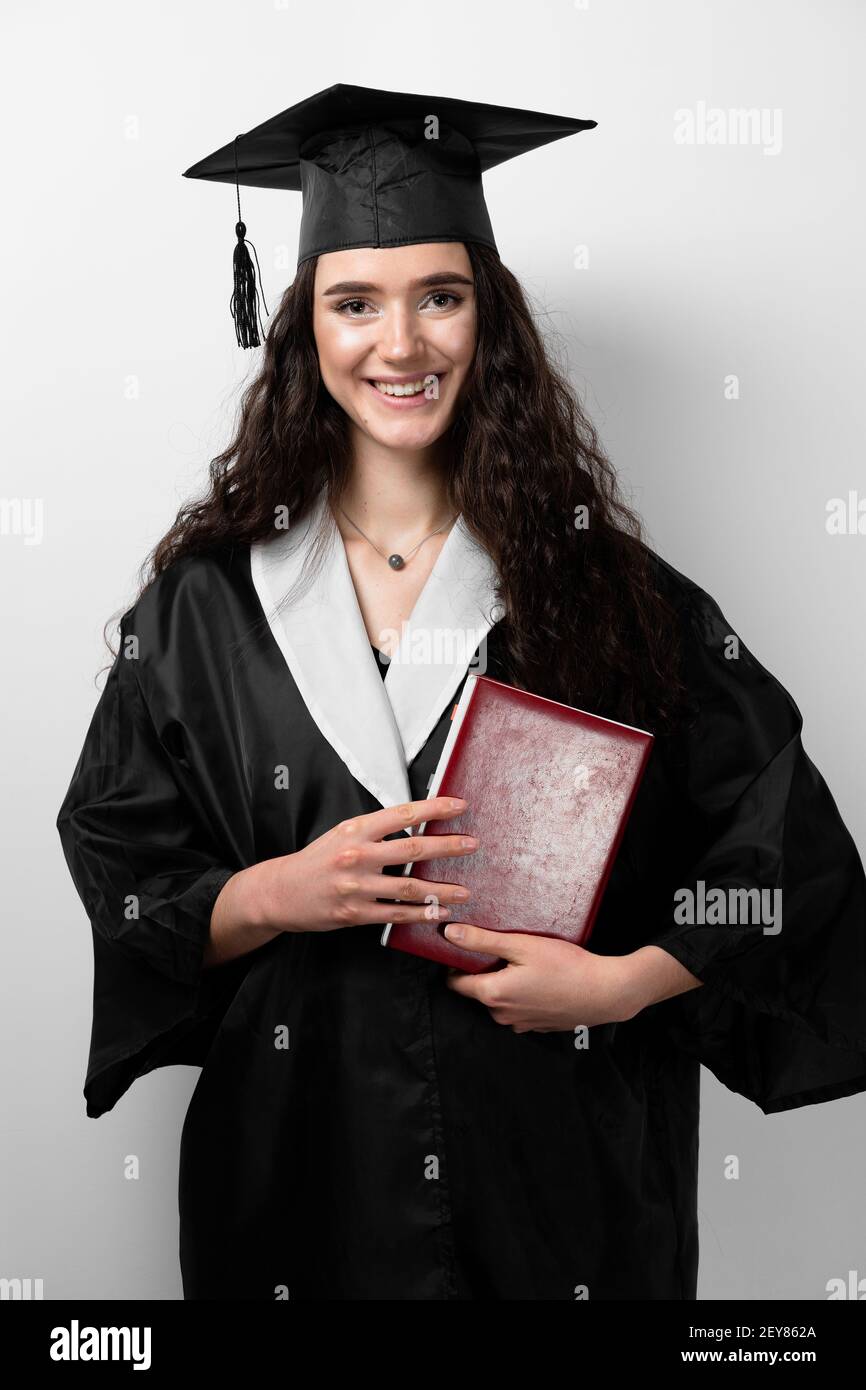 Student with book in graduation robe and cap ready to finish college ...