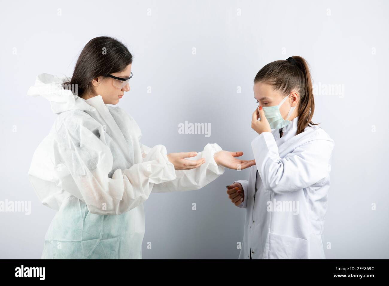 Female doctor in white uniform looking at a woman in defensive coat ...