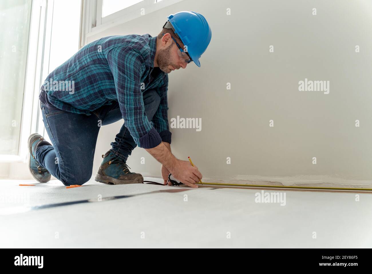 Builder man measuring for the installation of the wooden floor in the ...