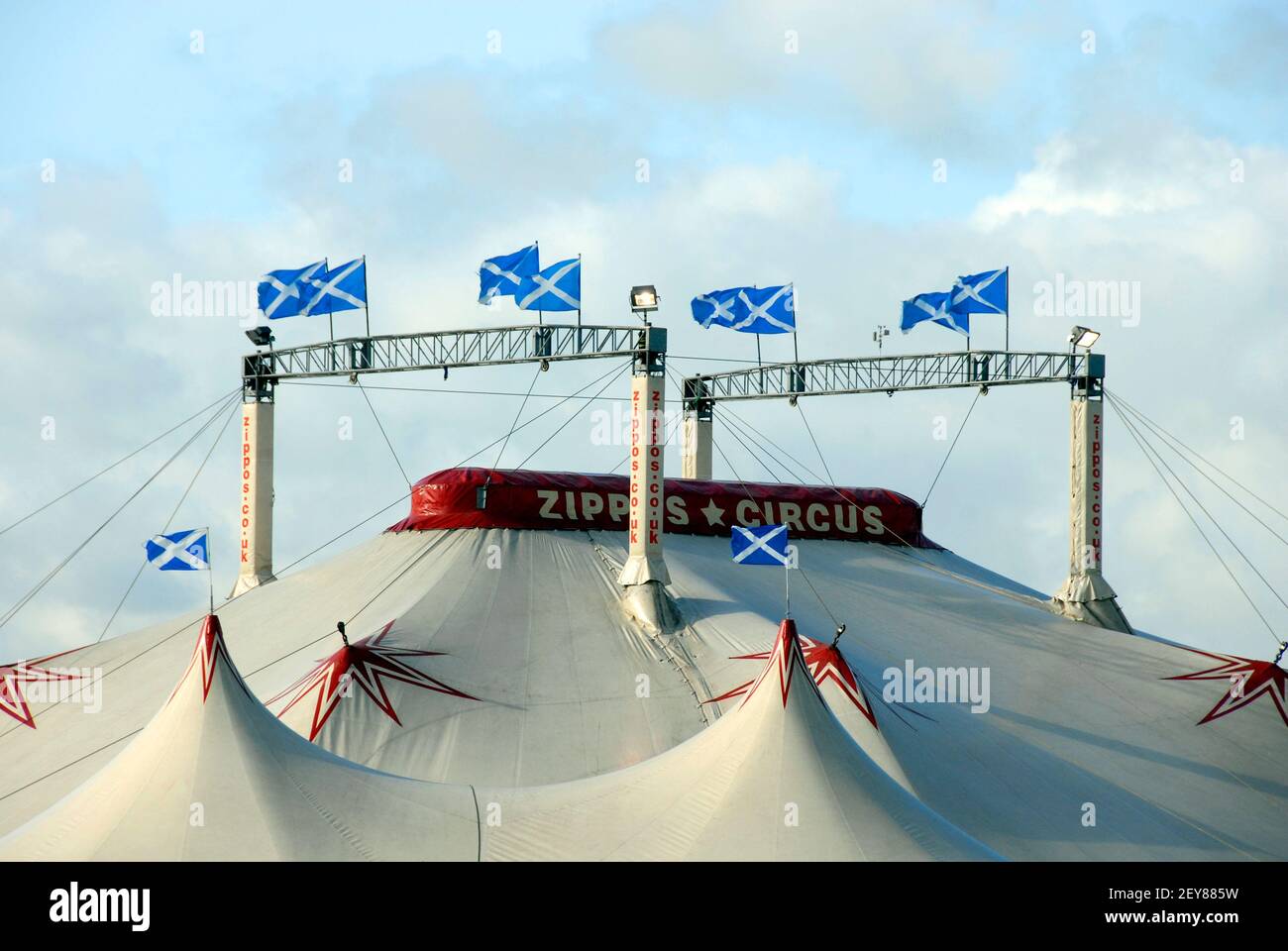Top of circus tent, Ayr, Scotland with Scottish flags flying in a stiff ...