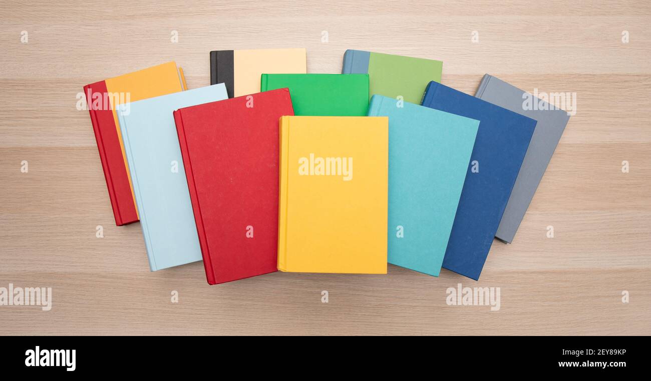 Top down view of a pile of bright colorful books centered on a light ...