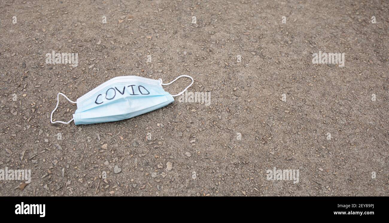 Mask with the word covid written on it laying on the sidewalk with copy ...