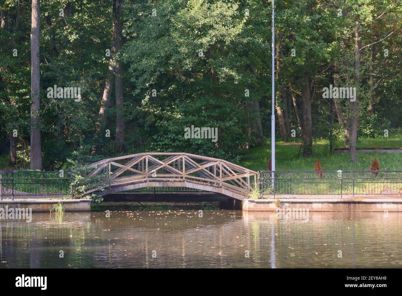 Arched wooden bridge with railing across lake in city park Stock Photo ...