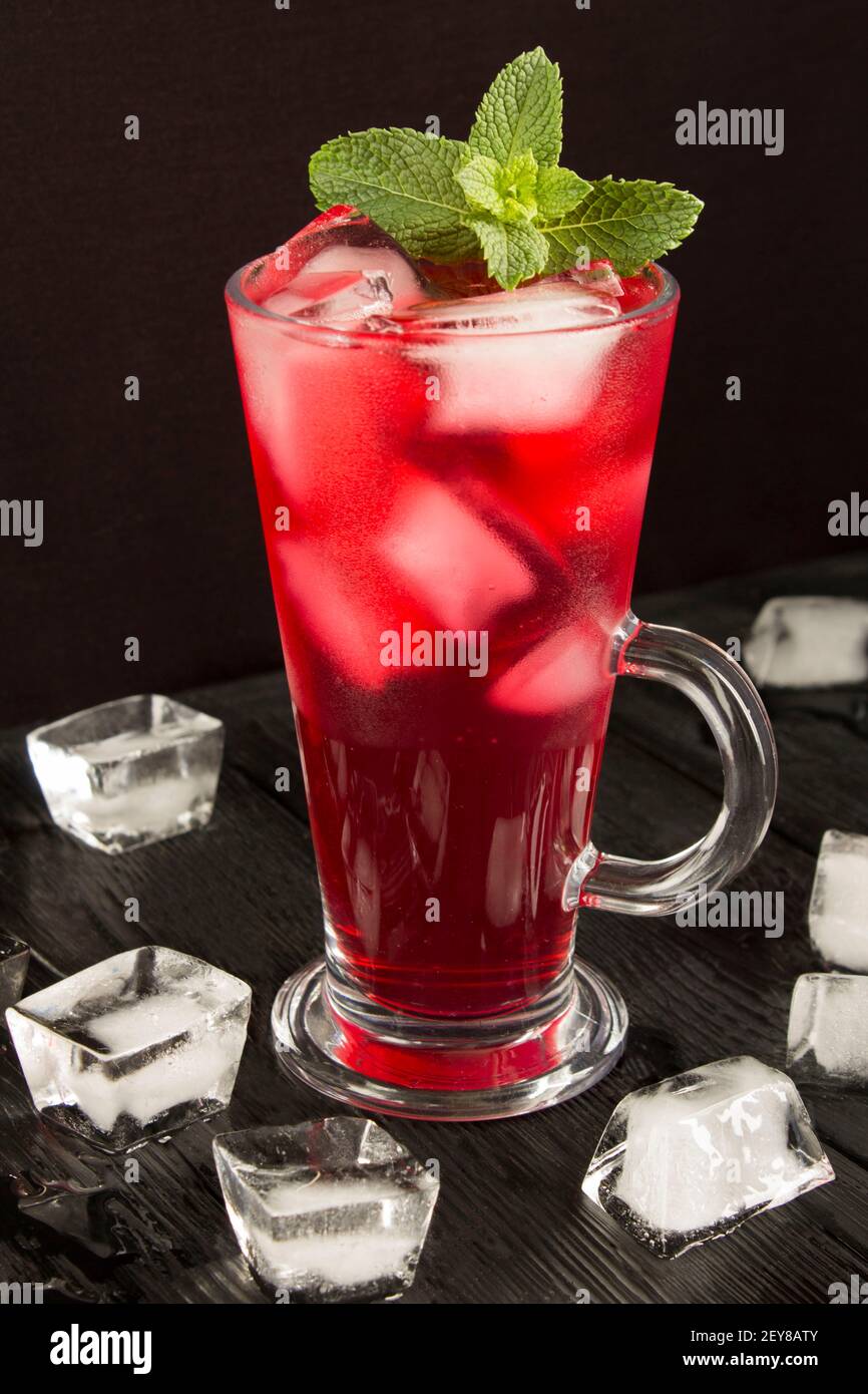 Cold pink lemonade with ice in the glass on the black background ...
