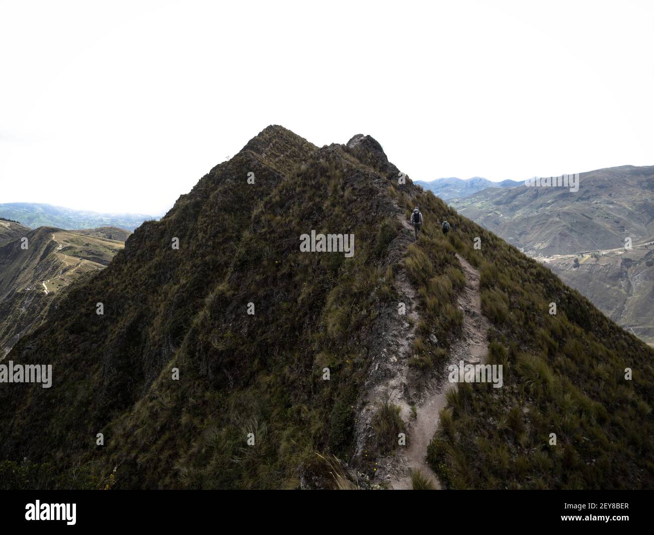 Hikers walking on andean volcano caldera crater lake Quilotoa rim ridge ...