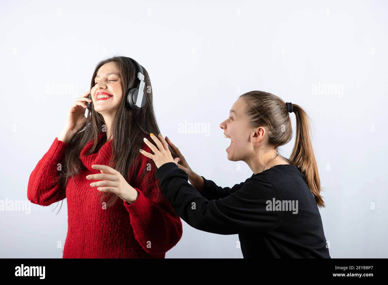 Young girl calling brunette woman in headphones on white background ...