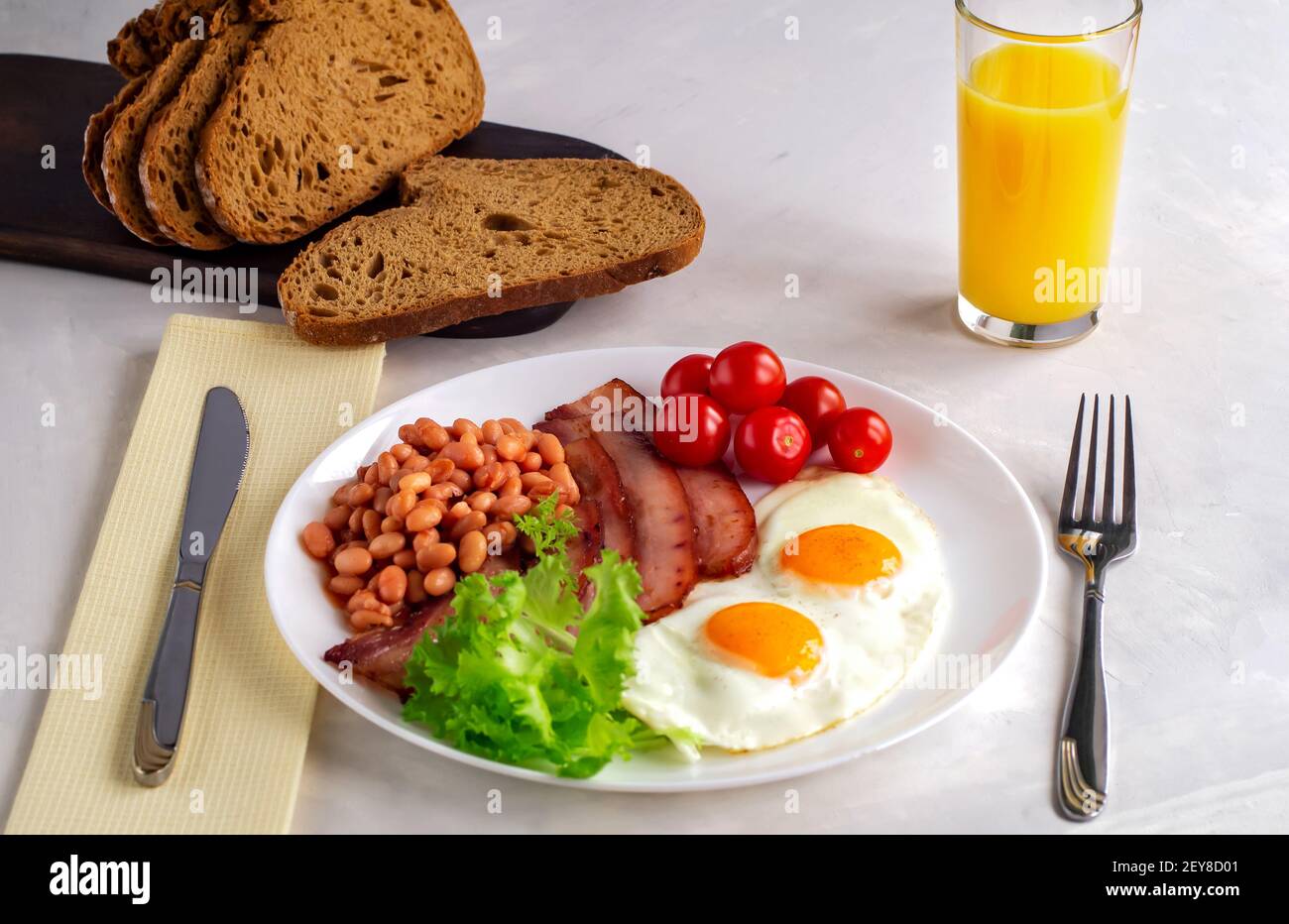 Hearty breakfast with scrambled eggs, bacon, beans, cherry tomatoes ...