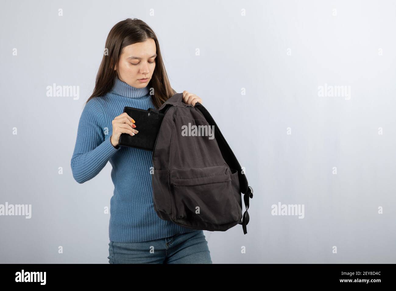 Image of a young girl student putting notebook in backpack Stock Photo ...