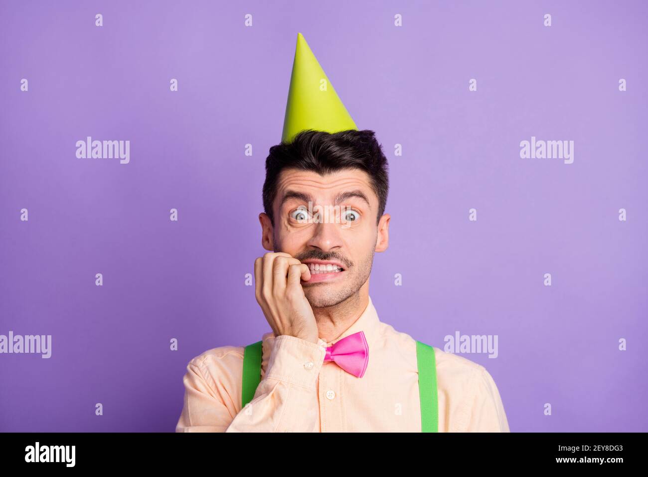 Photo of scared nervous young guy wear yellow shirt birthday cap biting ...