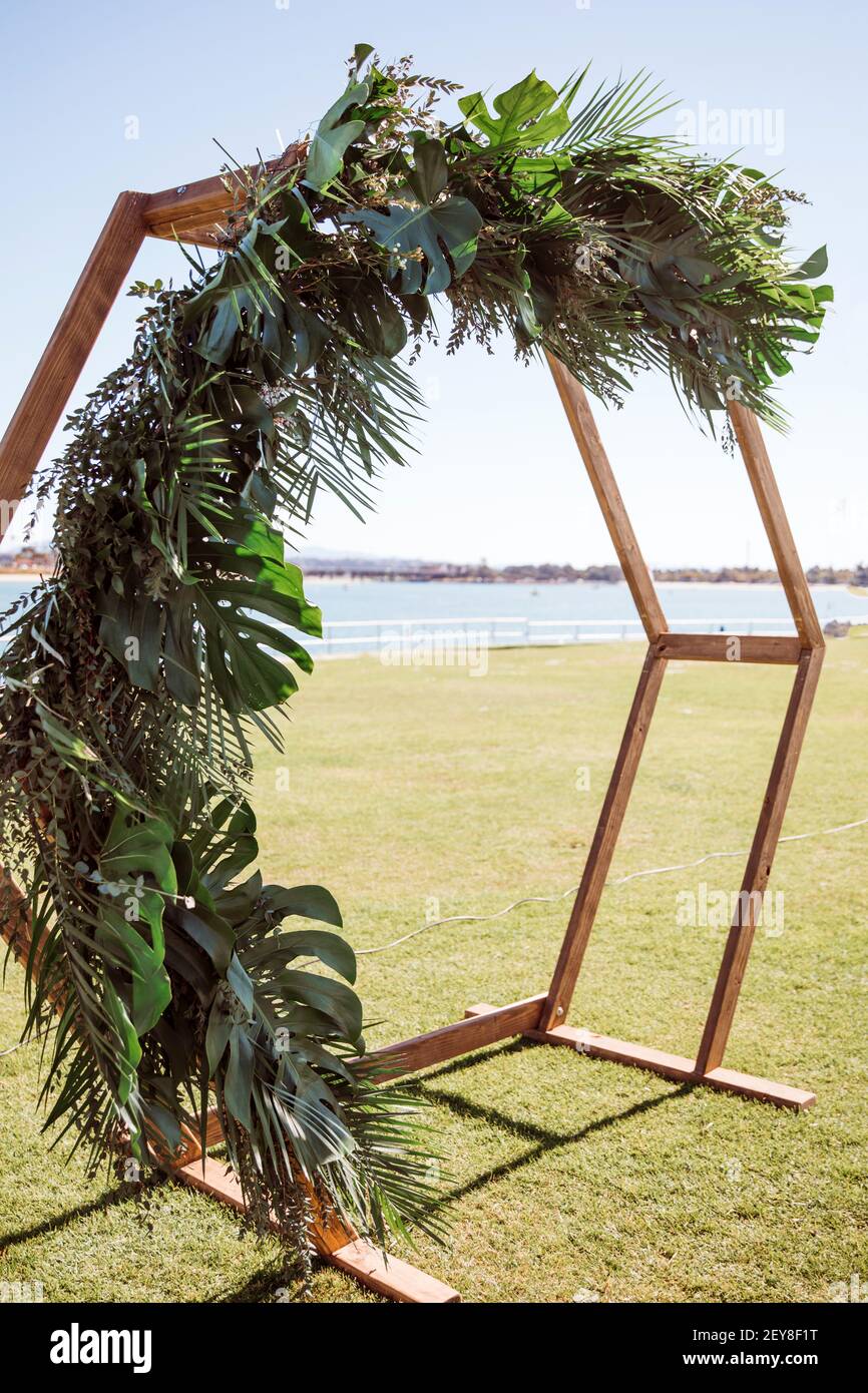 Wooden hexagon wedding arch with tropical leaves decor. Honeycomb ...