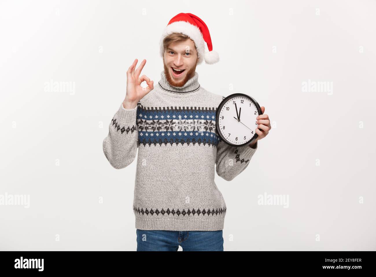 Holiday concept - Young handsome beard man in sweater with white clock ...