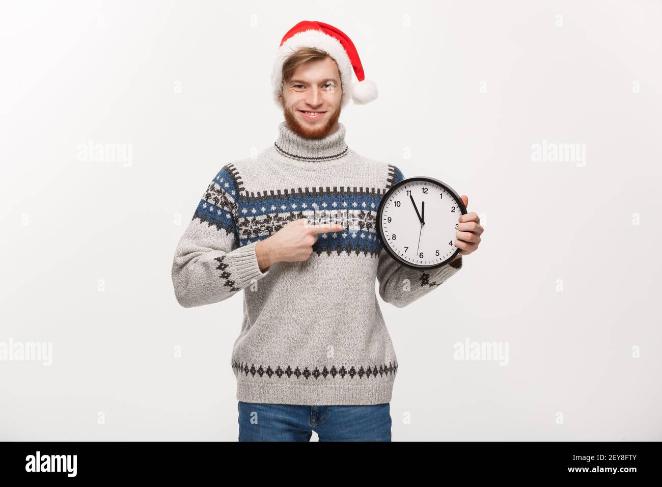 Holiday concept - Young handsome beard man pointing on white clock ...