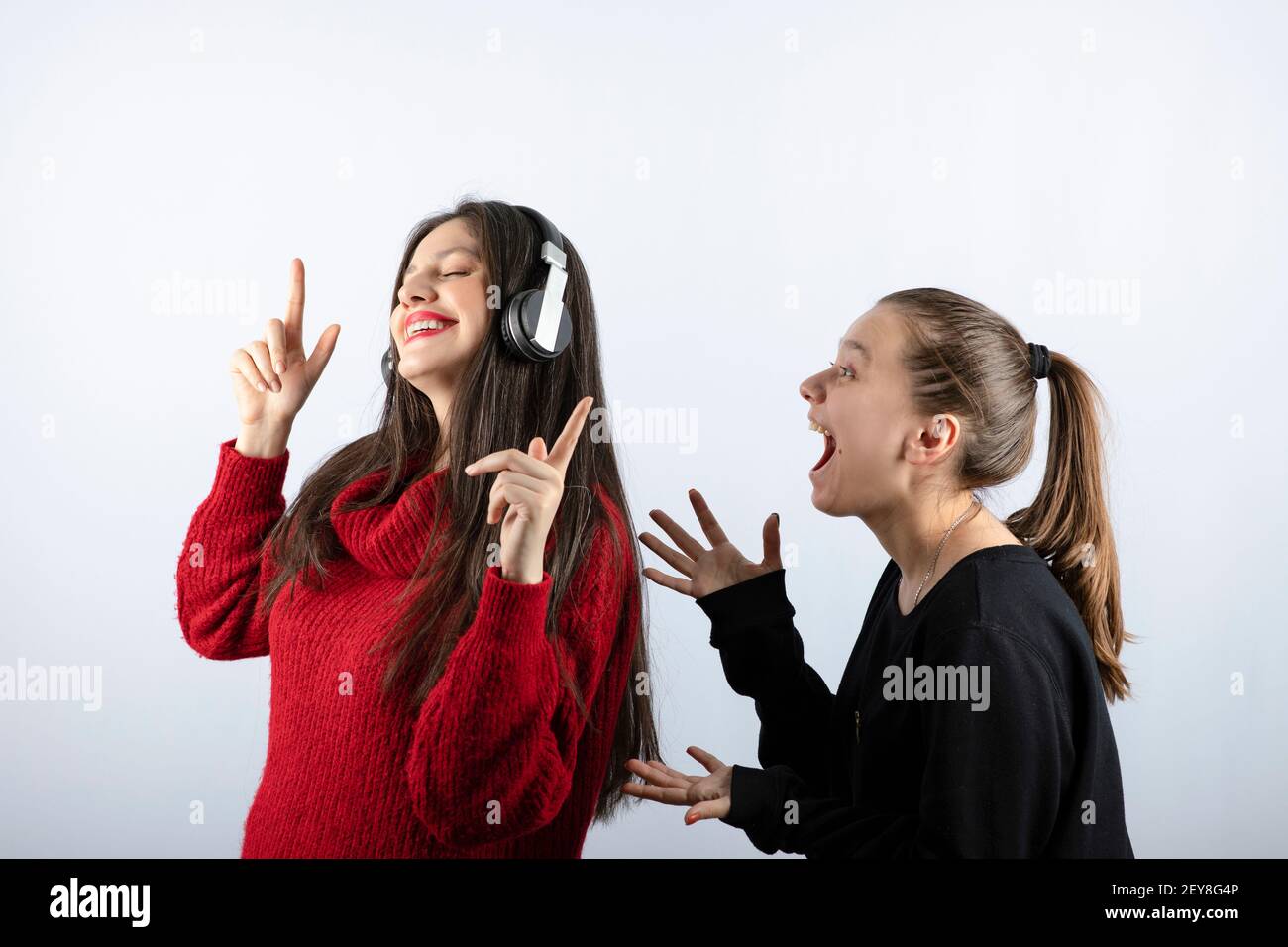 Young girl calling brunette woman in headphones on white background ...
