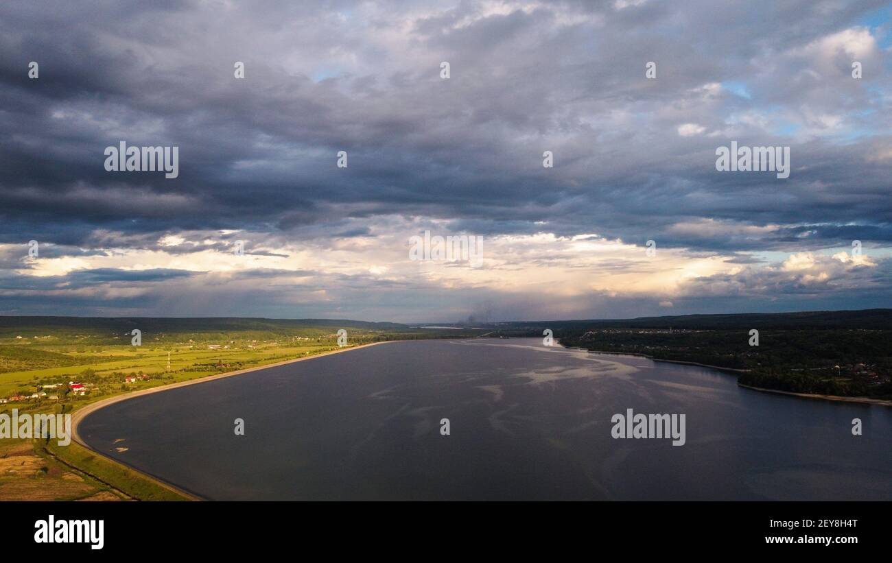 An aerial of a landscape with a flowing river gleaming under the cloudy ...